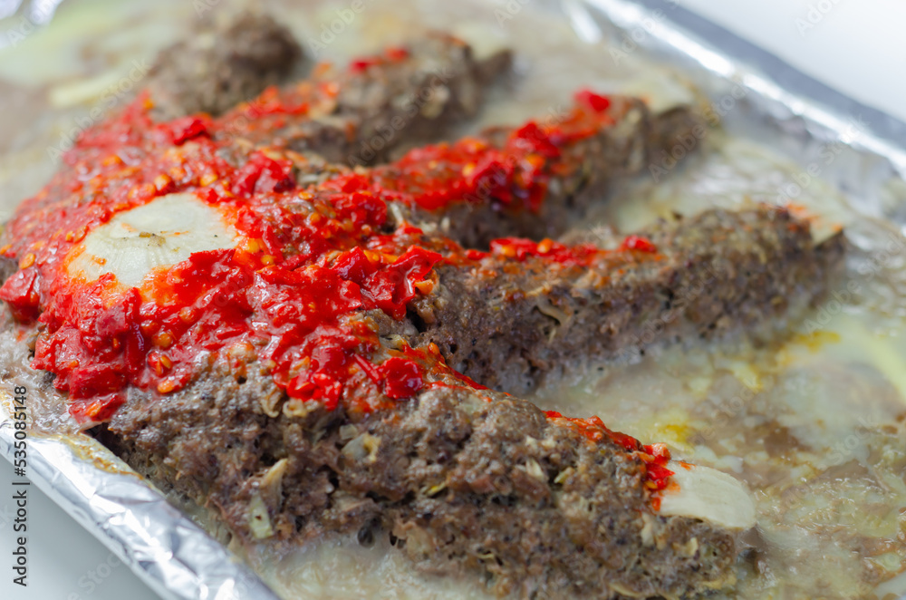 Roasted minced meat formed in the shape of a hand, topped with a tomato ...
