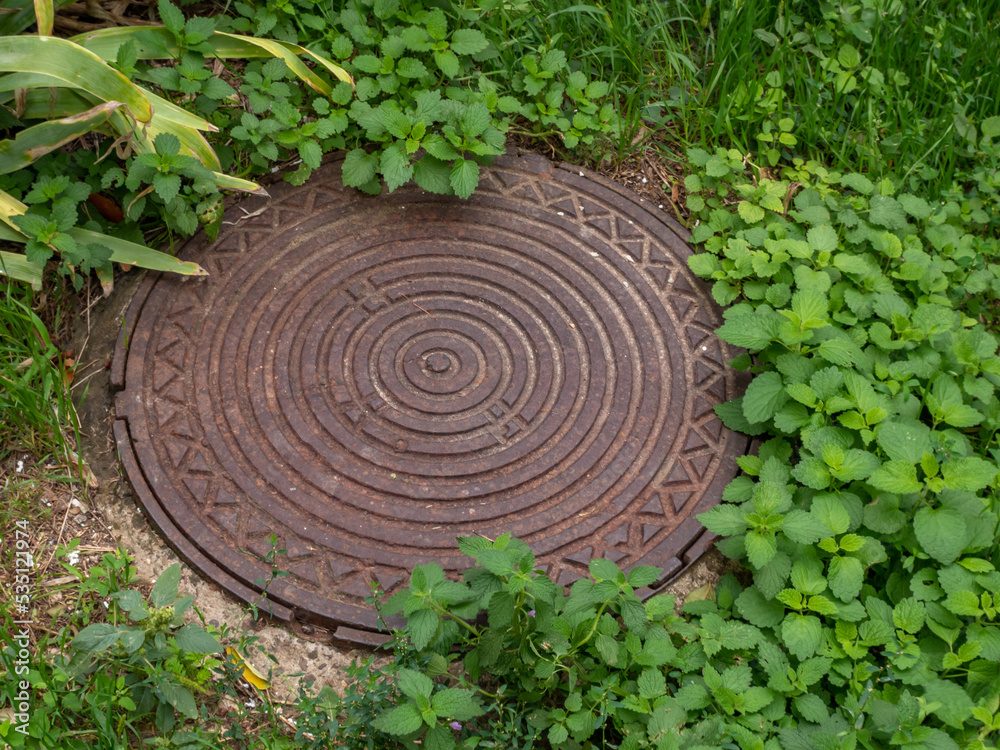 Iron manhole of the city sewer. A rusty manhole on a concrete base ...
