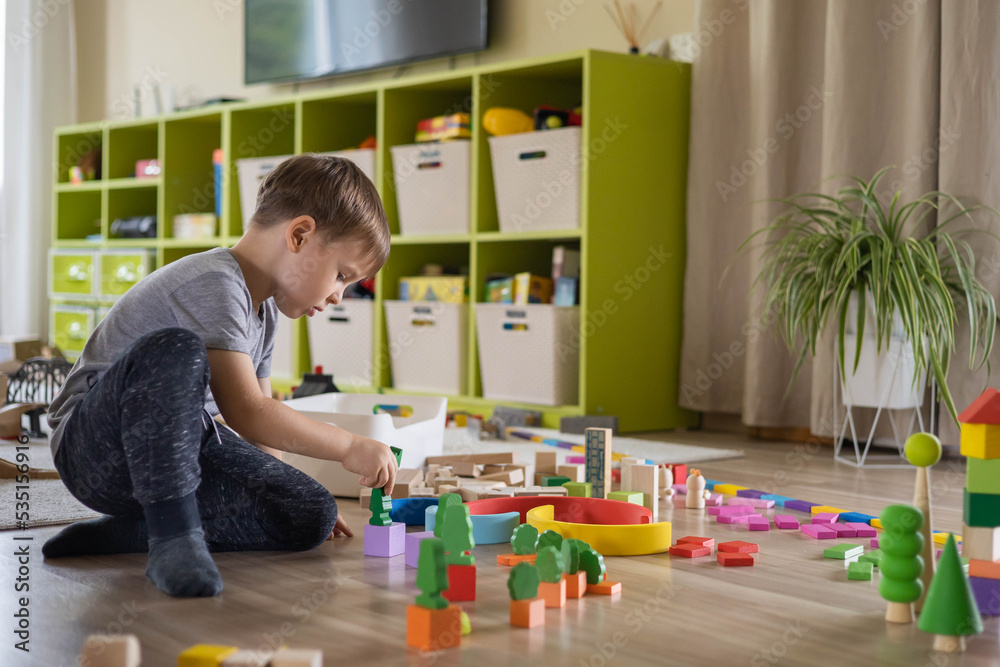 Confident male kid building fortress tower architecture wooden bricks ...
