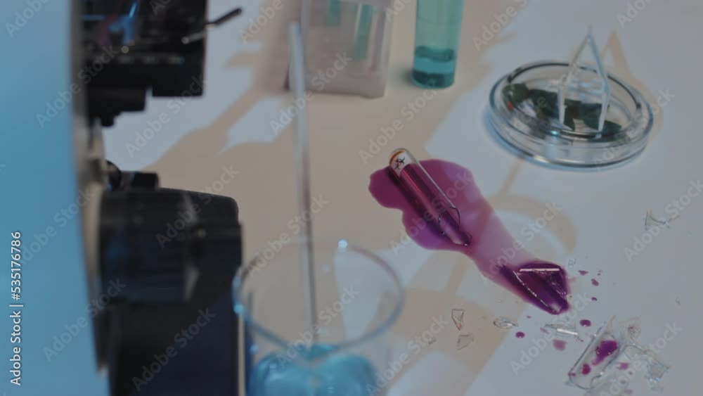 Top-down view of broken test tube with hazardous liquid on desk in ...