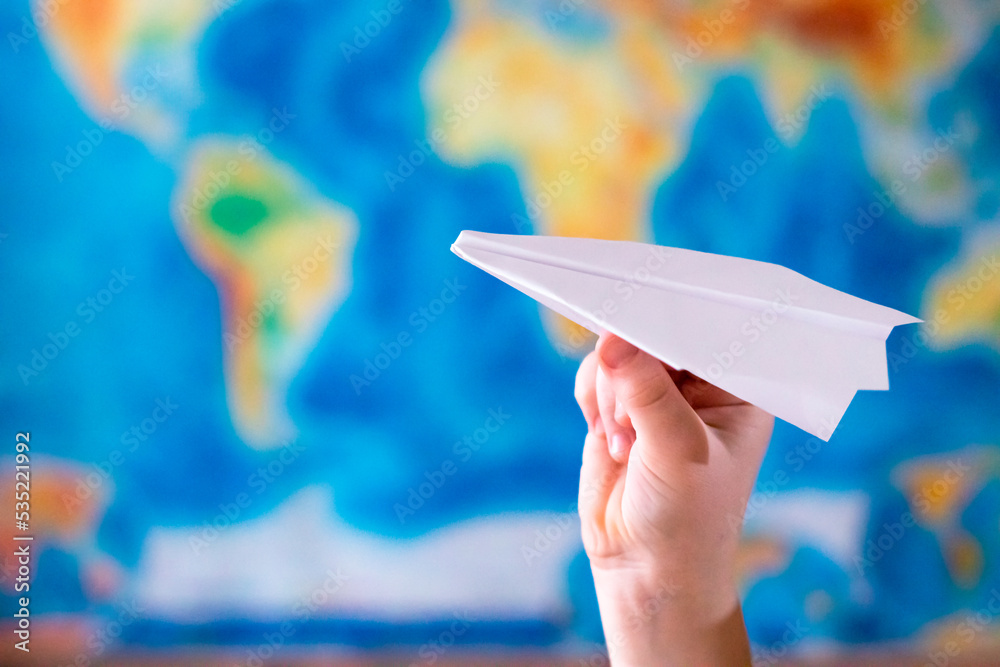 Сhild's hand holding white paper airplane on the background of colorful ...
