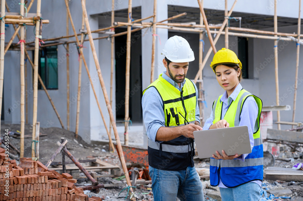 Construction man and woman in vest with helmet working with laptop ...