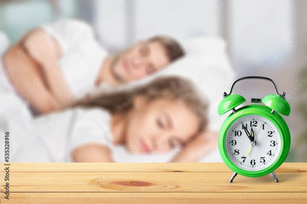 Classic alarm clock on bedside table in bedroom, with happy peaceful ...