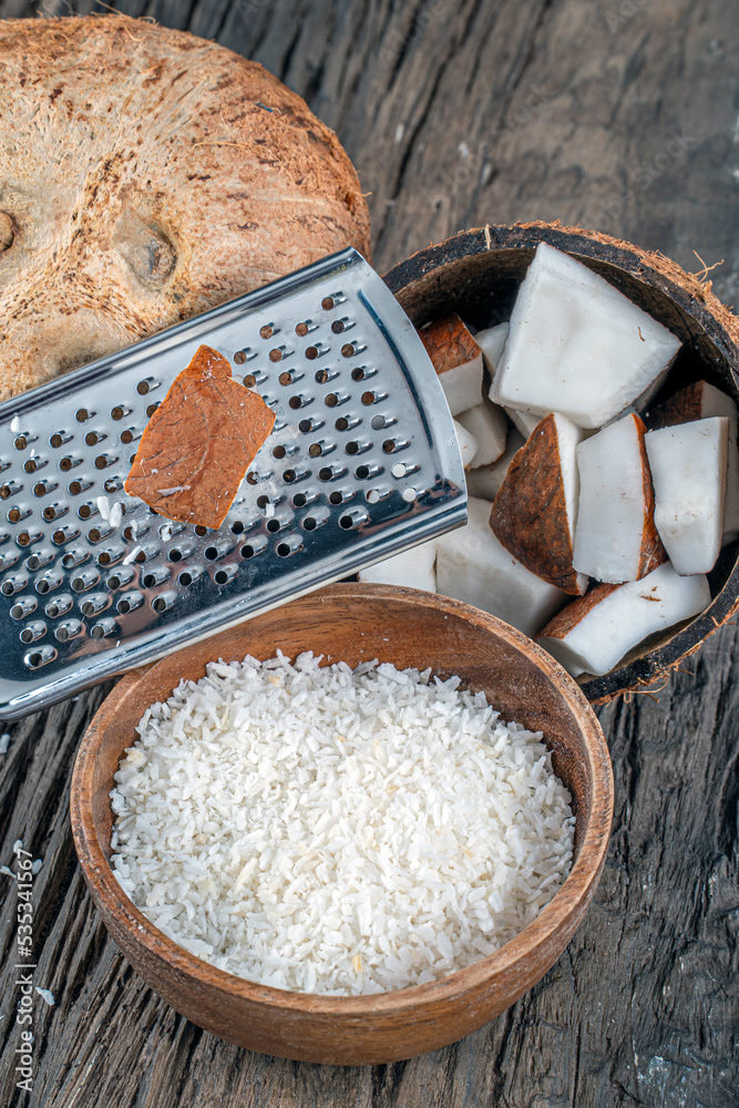 Whole,cut and grated coconut,fresh coconut slice is seen grating with a ...