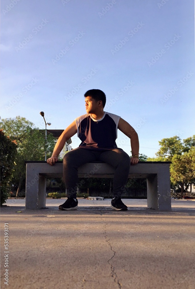 Man sitting on bench while glancing his right side surrounded with tall ...