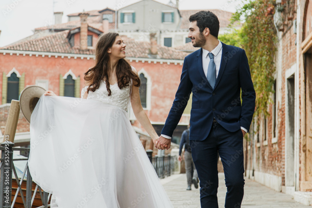 Young married couple roaming in the city doing photoshoot in wedding ...