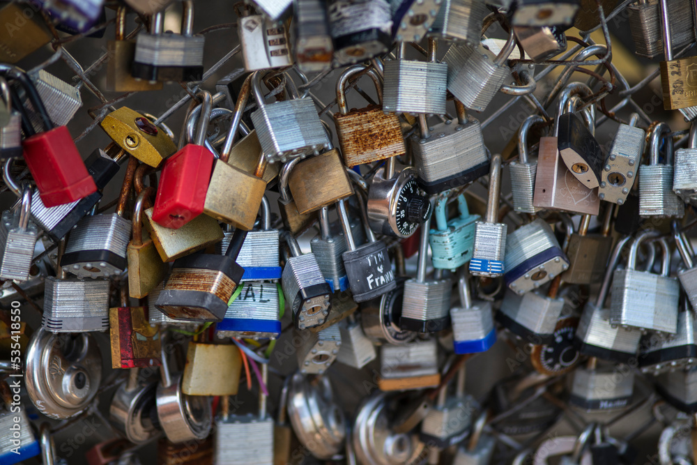 Old and new padlocks with names and dates written on them lock on a ...