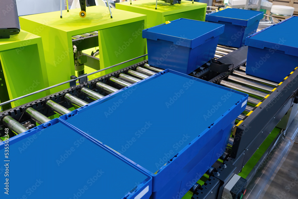 Automated conveyor. Blue boxes on moving band. Pipeline for fulfillment ...