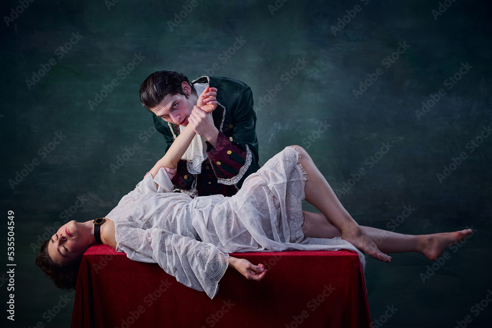 Portrait of man in image of vampire biting hand of young woman lying on ...