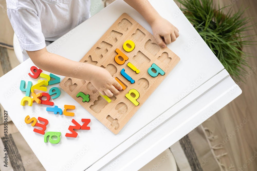 Male kid playing with wooden eco friendly alphabet letters board on ...
