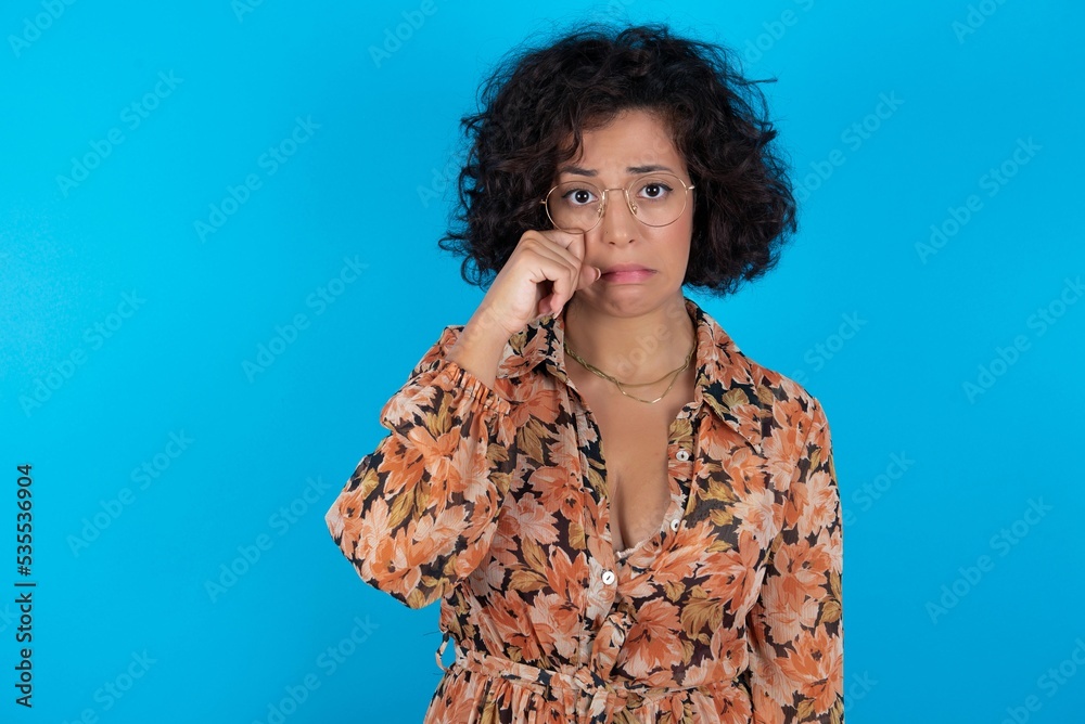 Disappointed dejected young brunette woman with curly hair wearing ...
