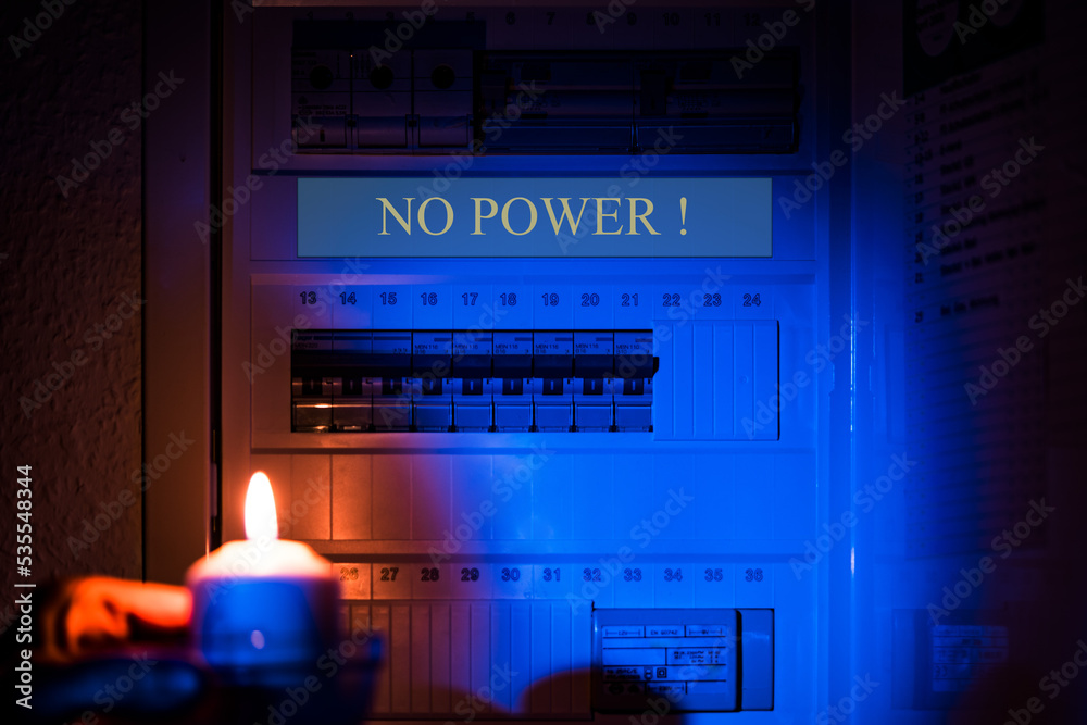 hand with candle in darkness room on electricity switch box. Power ...