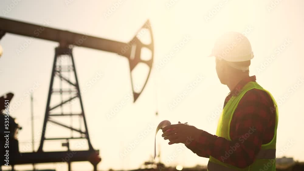 oil industry. engineer next to an oil rig signs a paper contract. oil ...
