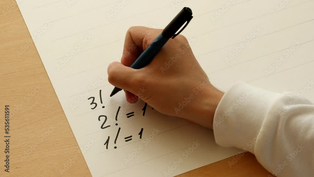 Hand of a young mathematician writing factorial numbers on the paper ...