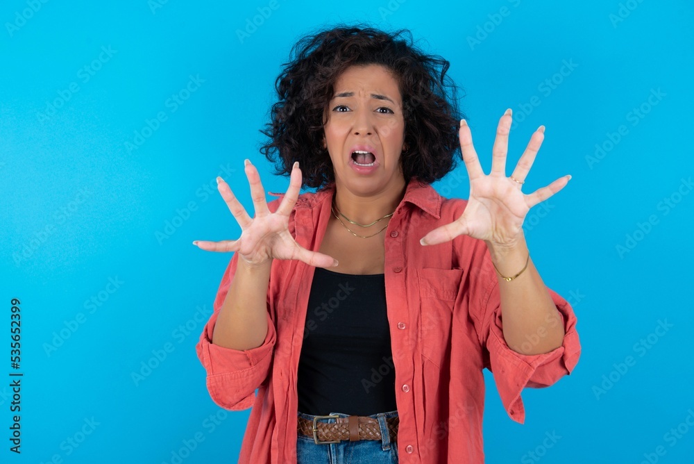 Dissatisfied young beautiful woman with curly short hair wearing red ...