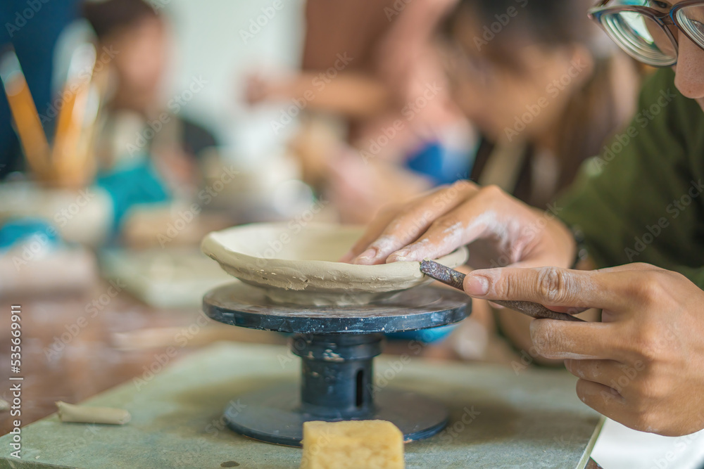 Man potter working on potters wheel making ceramic pot from clay in ...