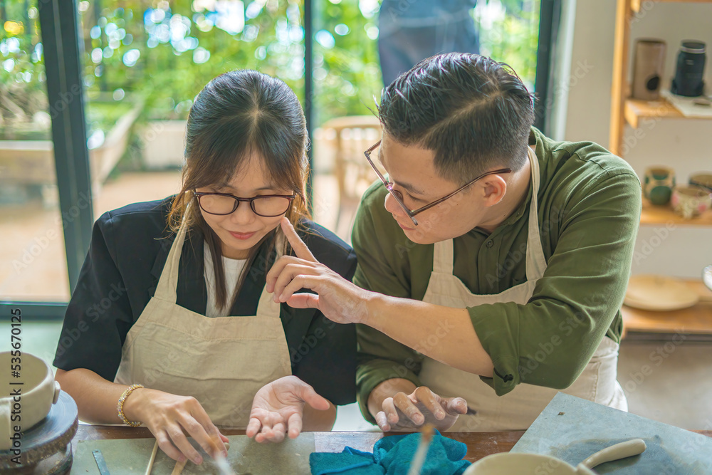 Focus couple potter working on potters wheel making ceramic pot from ...