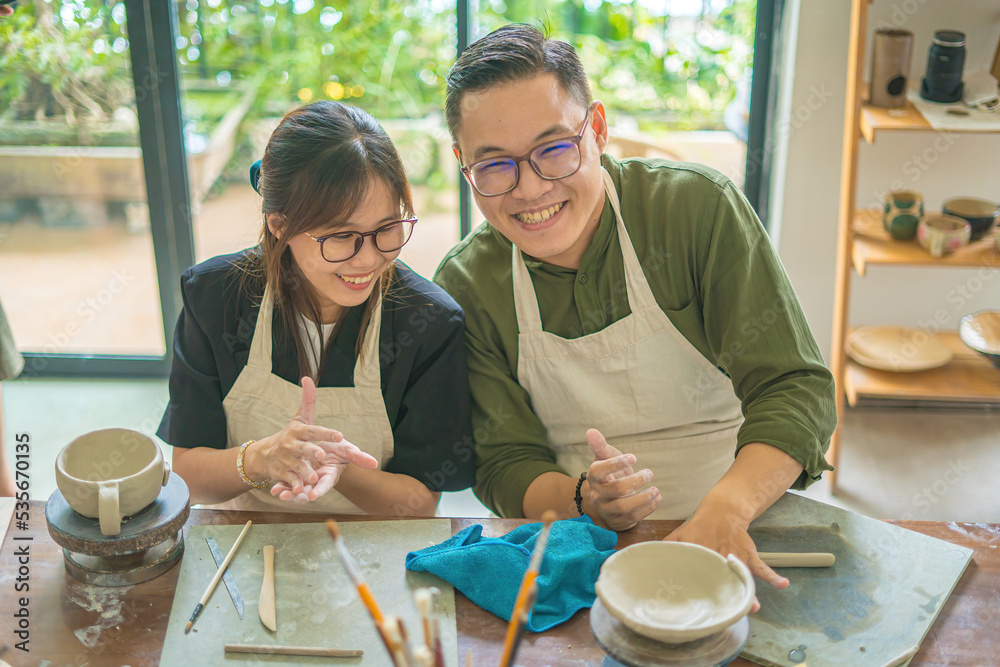 Focus couple potter working on potters wheel making ceramic pot from ...