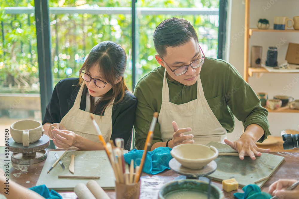 Focus couple potter working on potters wheel making ceramic pot from ...