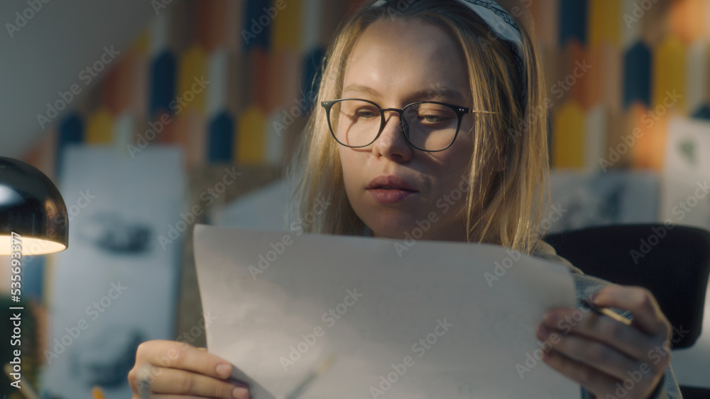 Female creative designer looks critically at her sketches for a comic ...