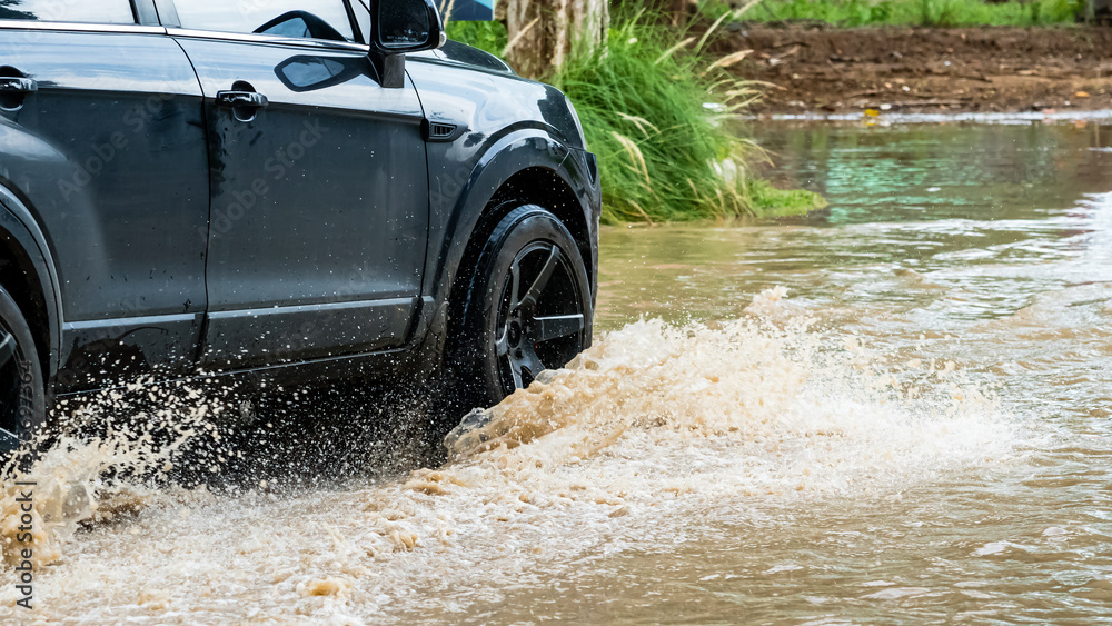 Car passing through a flooded road. Driving car on flooded road during ...
