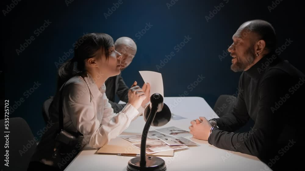 Police officers interrogate murder suspect. Detective cop shows photo ...