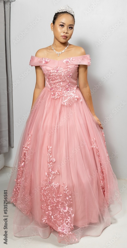 Vertical shot of a beautiful Filipino girl in a pink princess costume ...