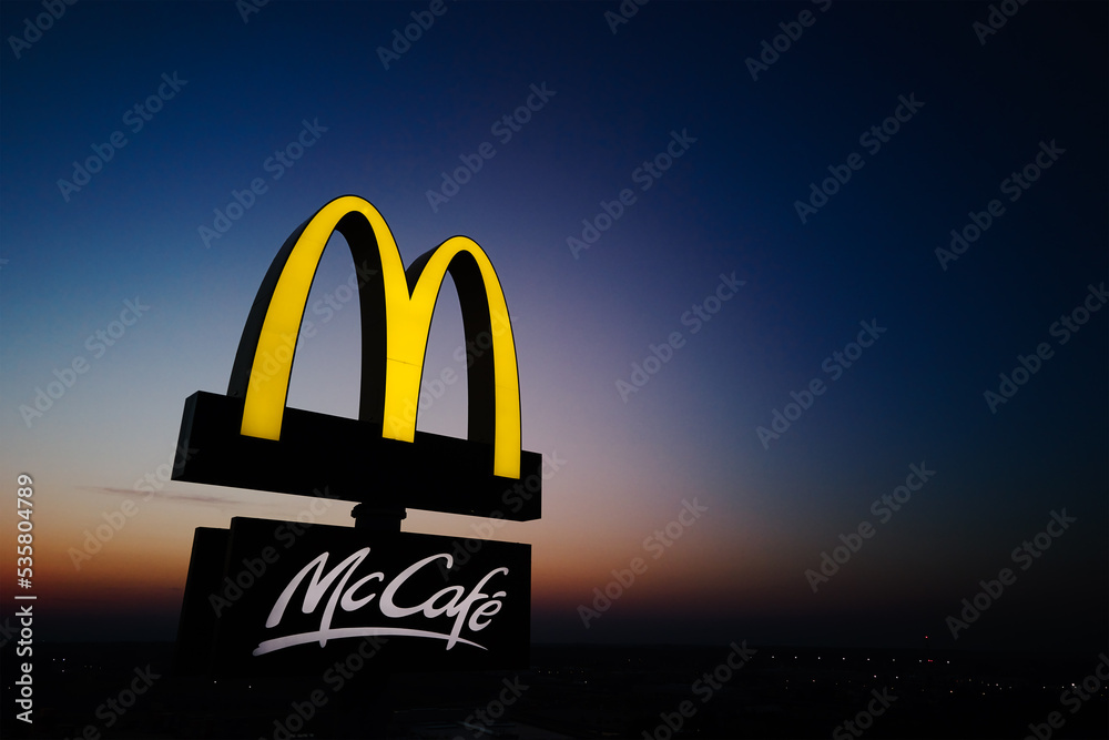 Glowing McDonalds restaurant sign against night sky. Logo of McCafe ...