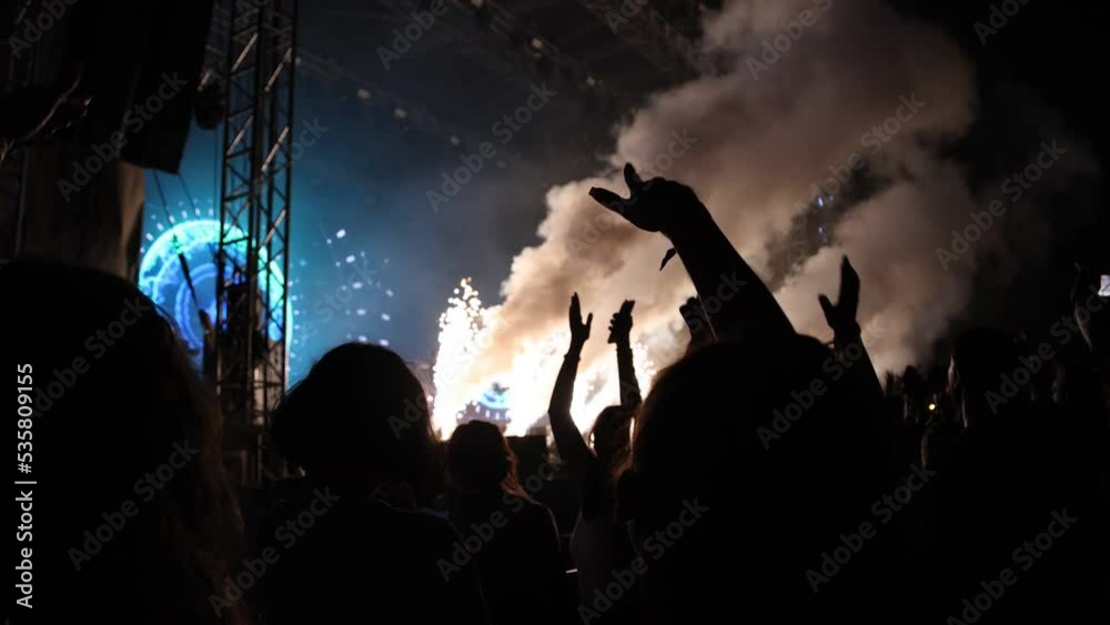 Smoke on concert stage with blinking lights, silhouettes of fans hands ...