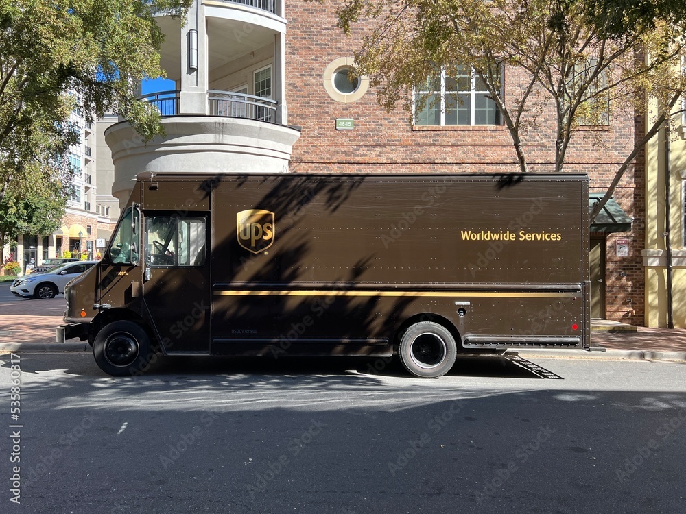 Iconic brown UPS United Parcel Service truck making deliveries in an ...