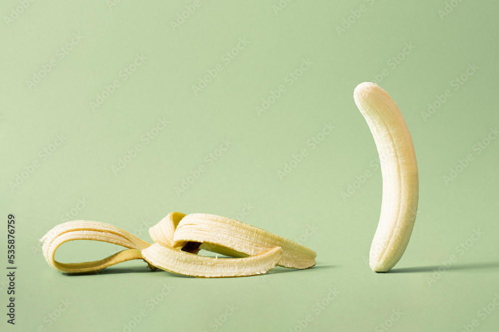 Creative idea made with standing banana and banana peel on pastel green ...