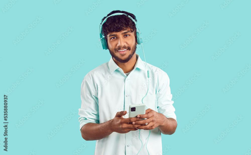 Modern devices. Portrait of happy young Indian man in headphones and ...