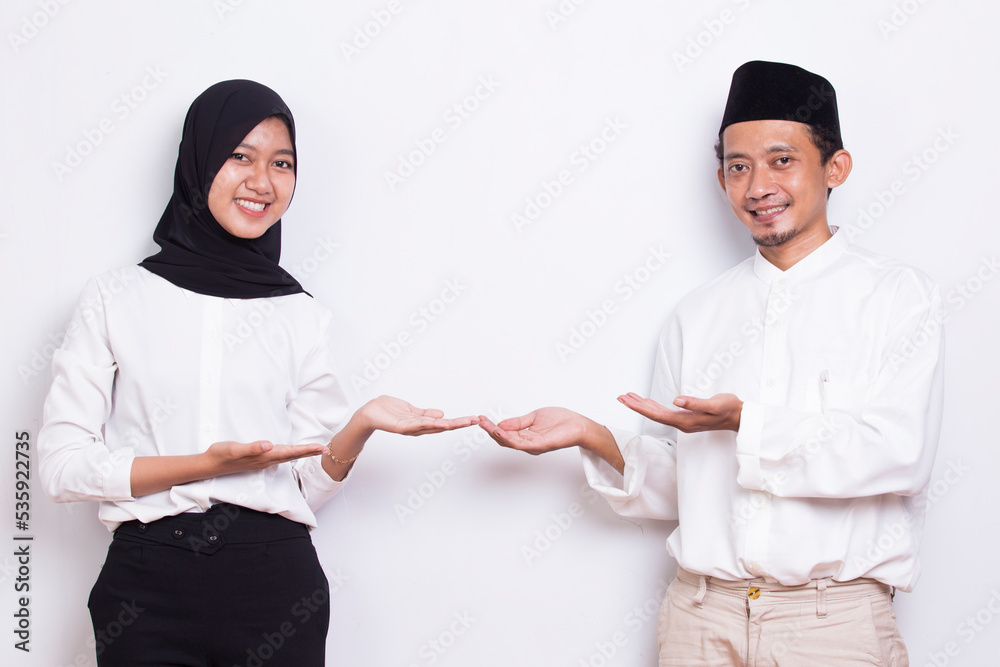 young asian muslim couple pointing with fingers to different directions ...