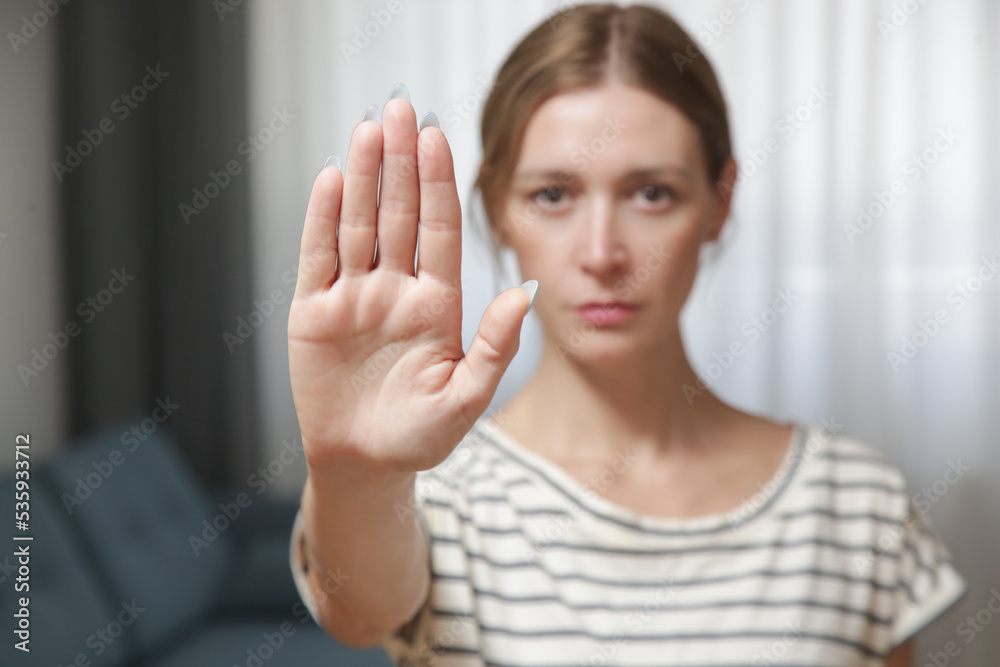 Serious worried young woman making hand stop gesture expressing ...