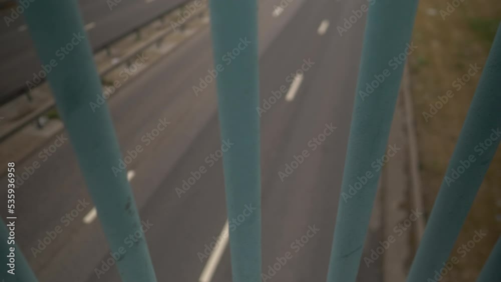 Cars pass under bridge with bars in foreground Stock Video | Adobe Stock