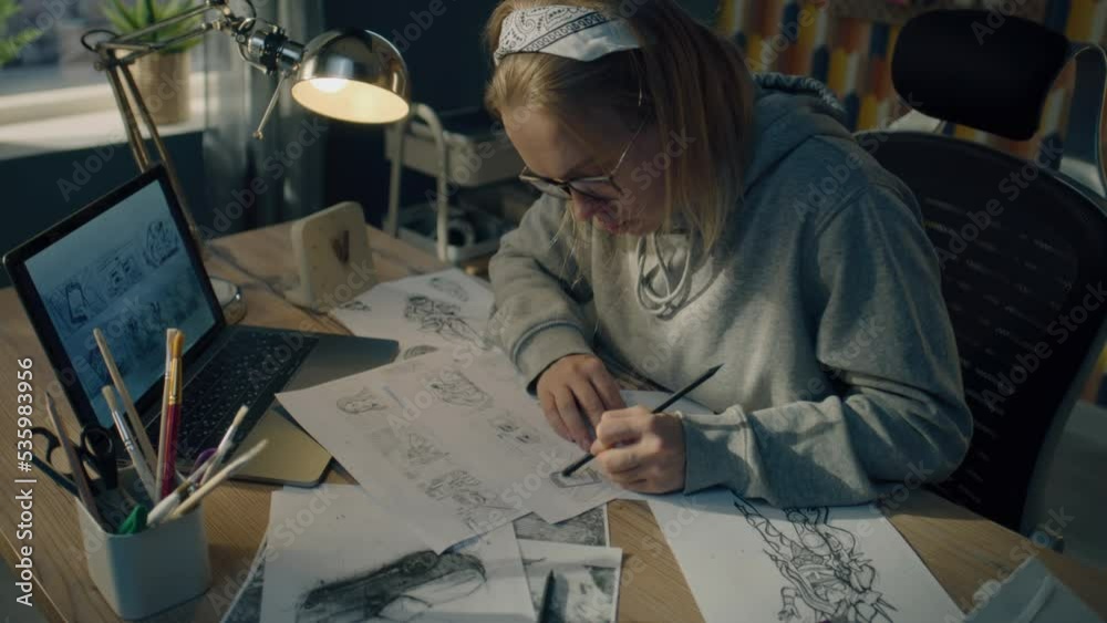 Female animator creates sketches for the cartoon. Looks at the laptop ...