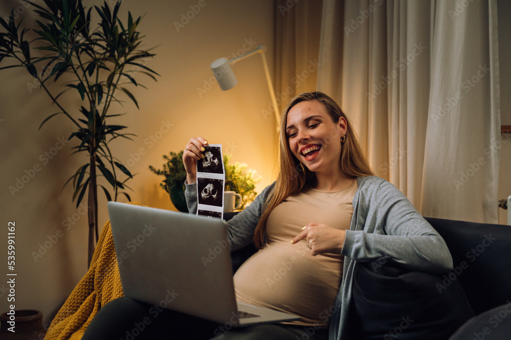 caucasian pregnant woman showing ultrasound photo on video call while ...