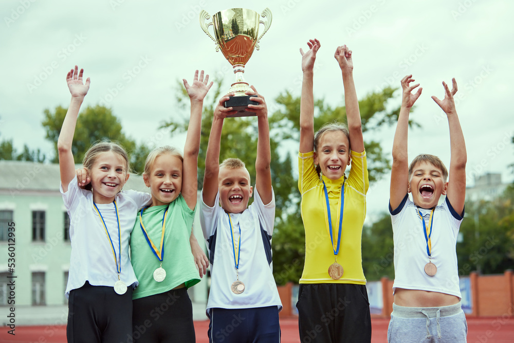 A boys and girls celebrating a victory. Motivated children team rising ...
