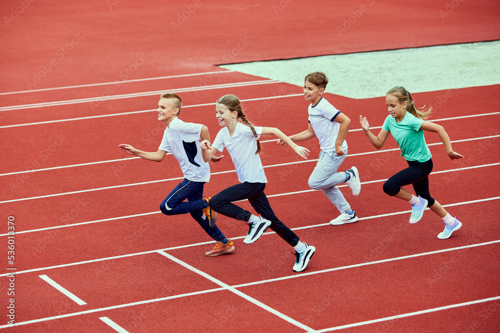 Group of children running on treadmill at stadium or arena. Little fit ...