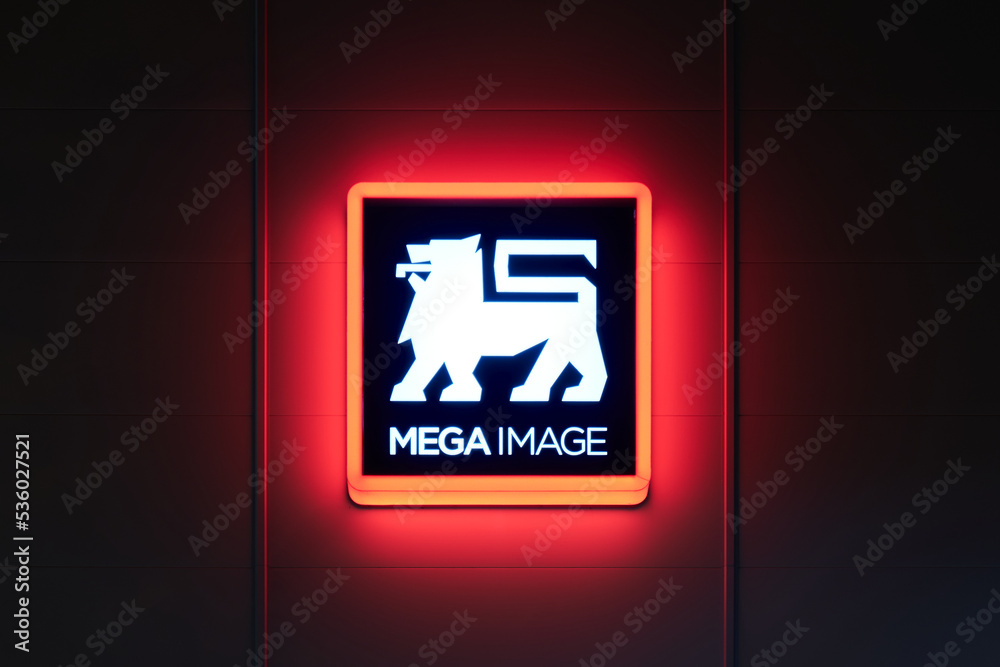 Illuminated Mega Image logo sign at night. Mega Image is a supermarket ...