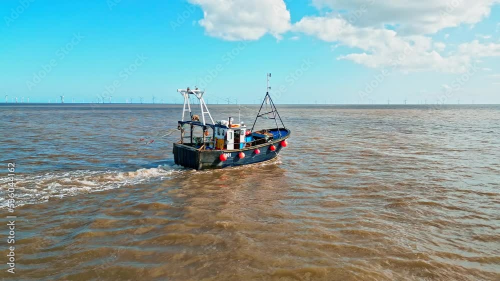 Aerial, video footage of a fishing trawler, boat, ship trawling for ...