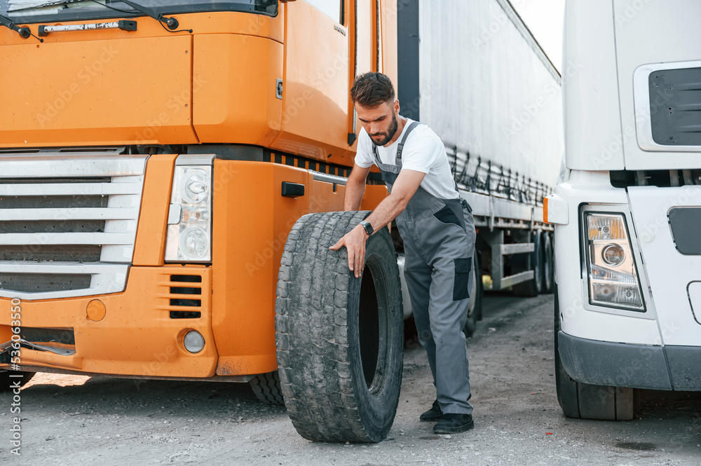 Changing the tire. Man in unifrom doing service for big truck vehicle ...