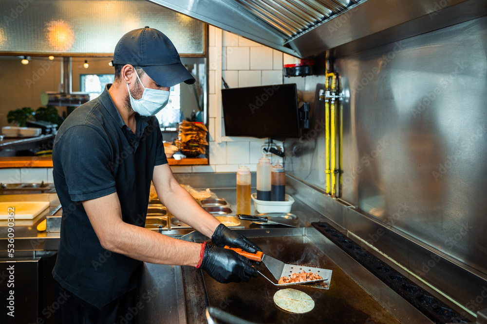 Cook in sterile mask preparing delicious taco in restaurant kitchen ...