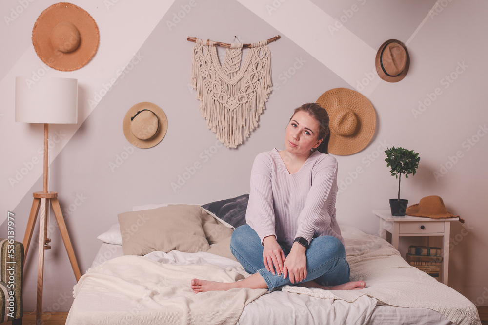 Pretty 25-year-old girl at home on bed in sweater and jeans Stock Photo ...