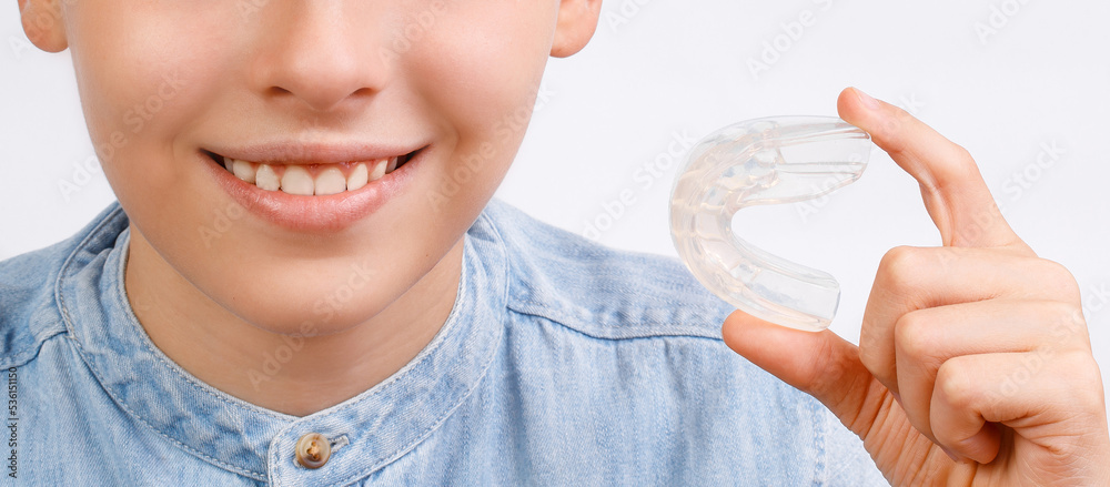 Positive child boy is holding mouth guards for his teeth and smiling ...