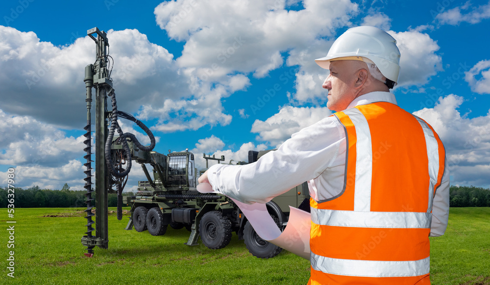 Drilling of wells. Man builder in orange vest back to camera. Builder ...