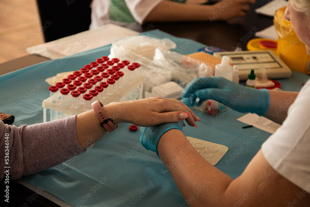 donor's day. a nurse in blue latex gloves takes a blood sample from a ...