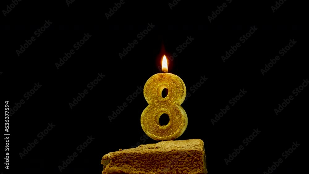 Festive cake with a lit number 8 candle on a black background on a ...
