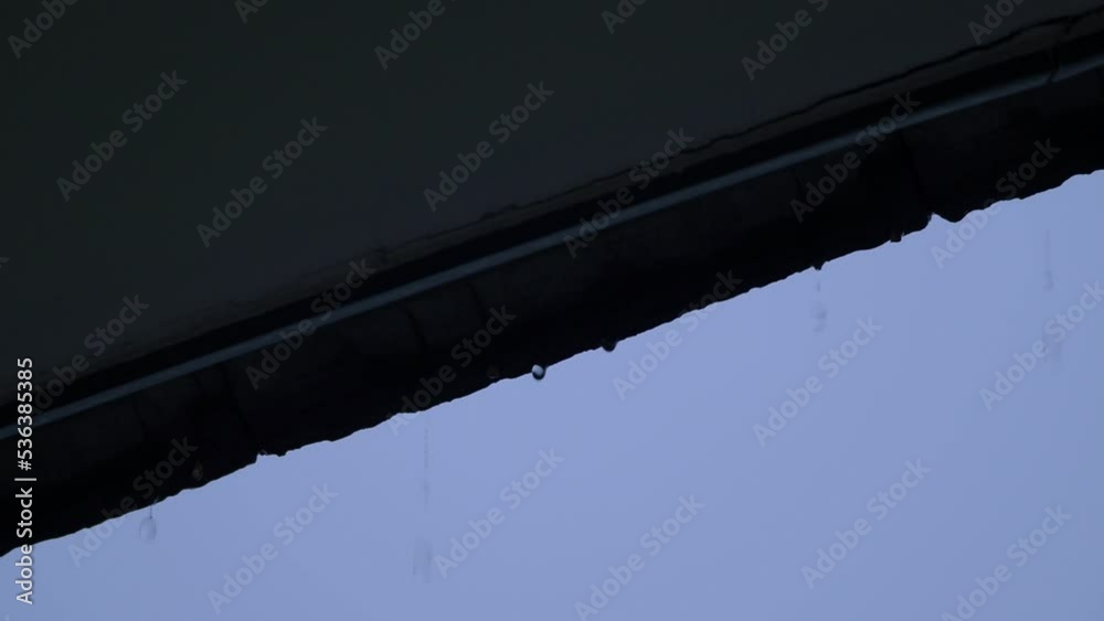 Rain and roof. Falling rain from the roof. Rain drops flow down from a ...