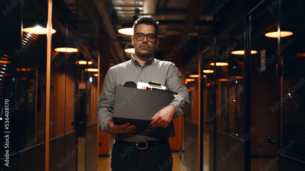 Fired upset man in suit walking down in office hallway, holding box ...